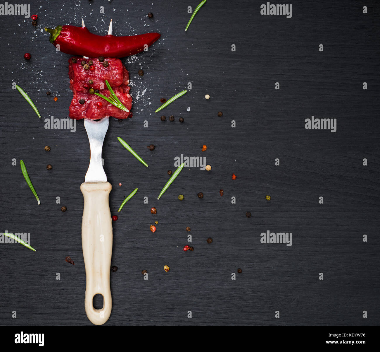 two pieces of beef and red chili pepper strung on a kitchen plug on a ...