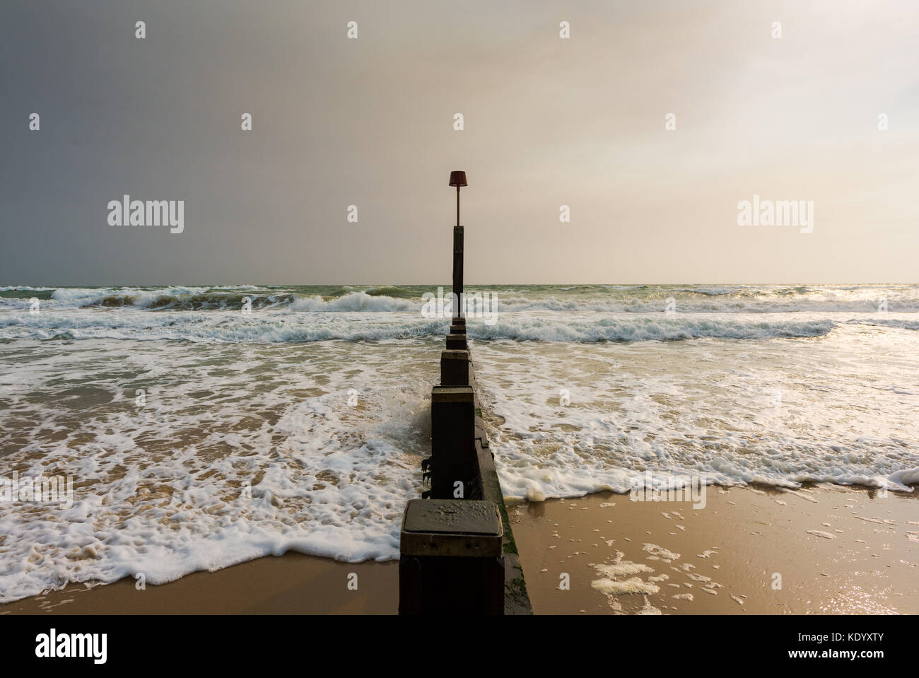 A wave breaker or groyne breaking waves as they roll up the beach under ...