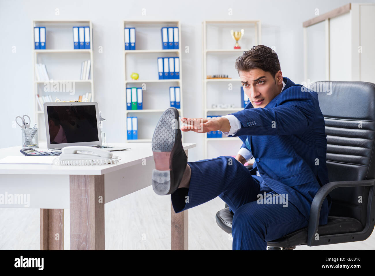 Young businessman doing sports stretching at workplace Stock Photo - Alamy