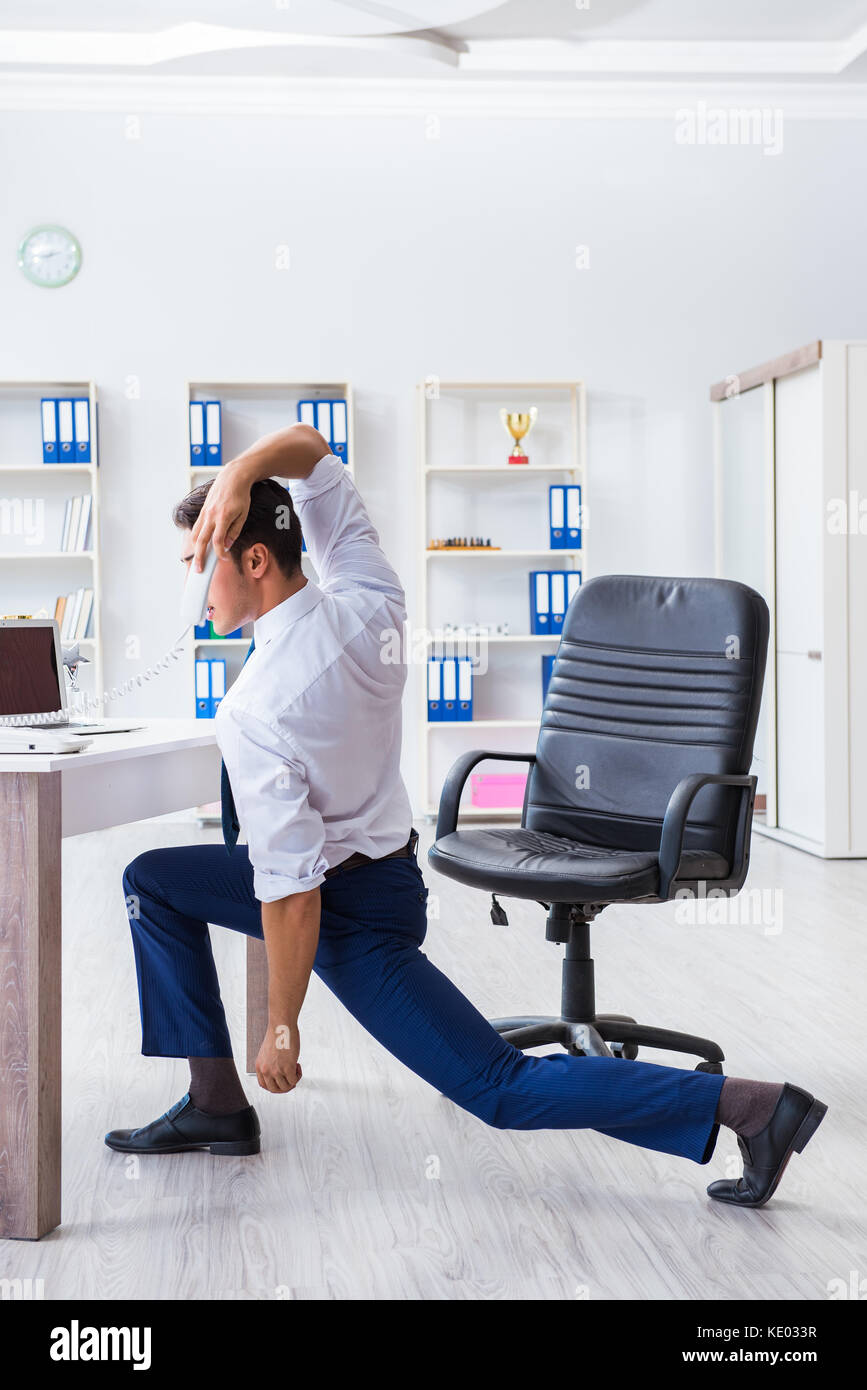 Young businessman doing sports stretching at workplace Stock Photo - Alamy