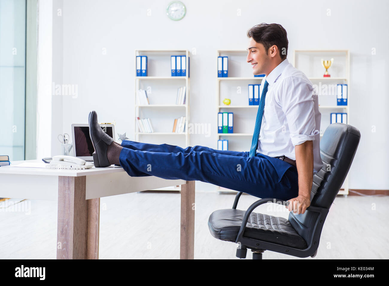 Young businessman doing sports stretching at workplace Stock Photo - Alamy