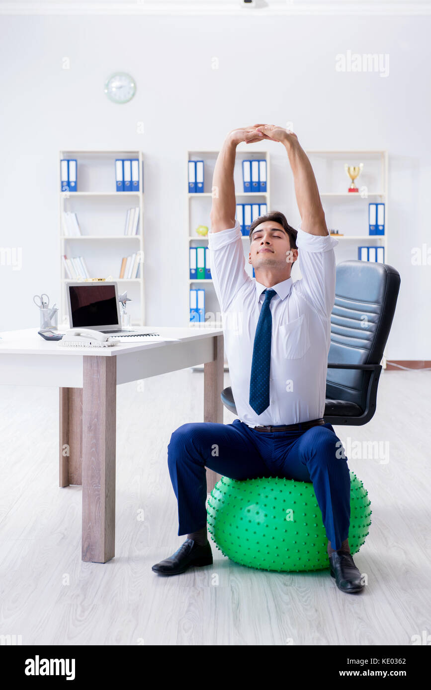 Young businessman doing sports stretching at workplace Stock Photo - Alamy