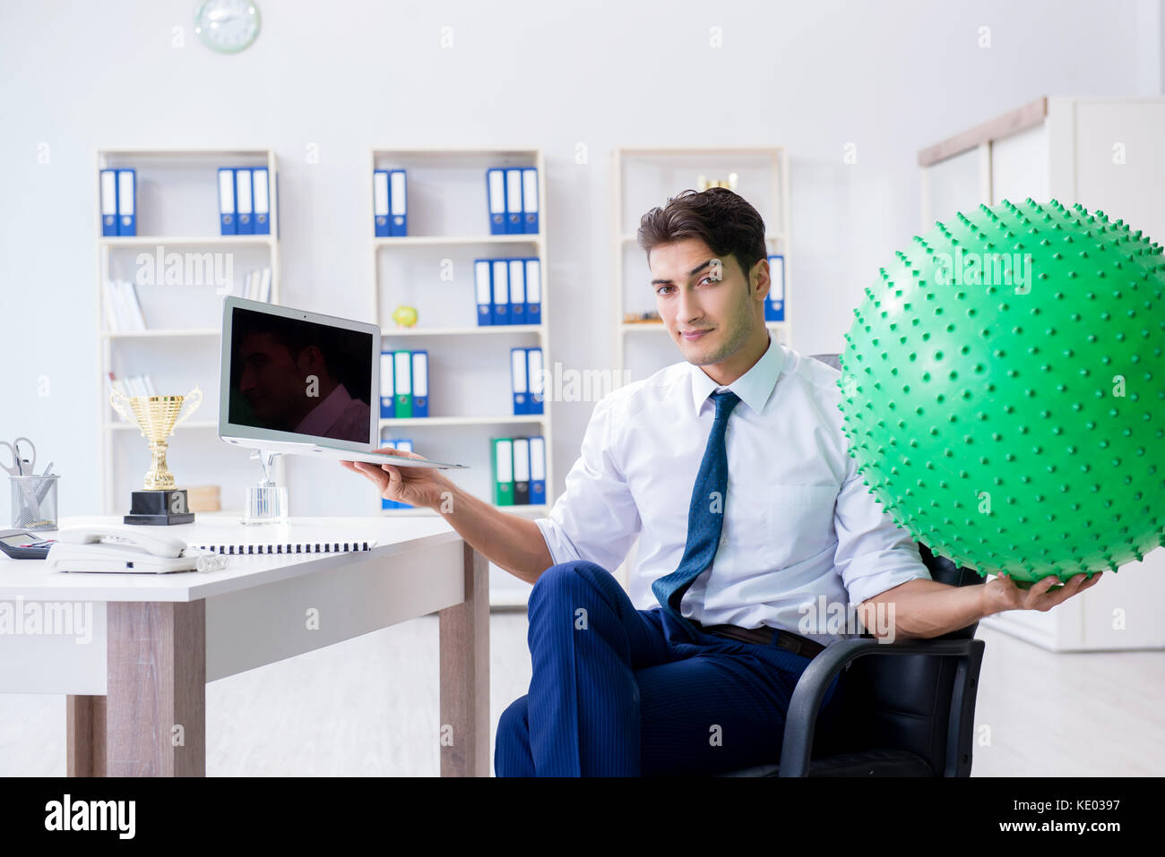 Young businessman doing sports stretching at workplace Stock Photo - Alamy