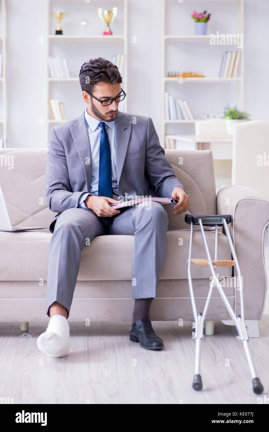Businessman with crutches and broken leg at home working Stock Photo ...