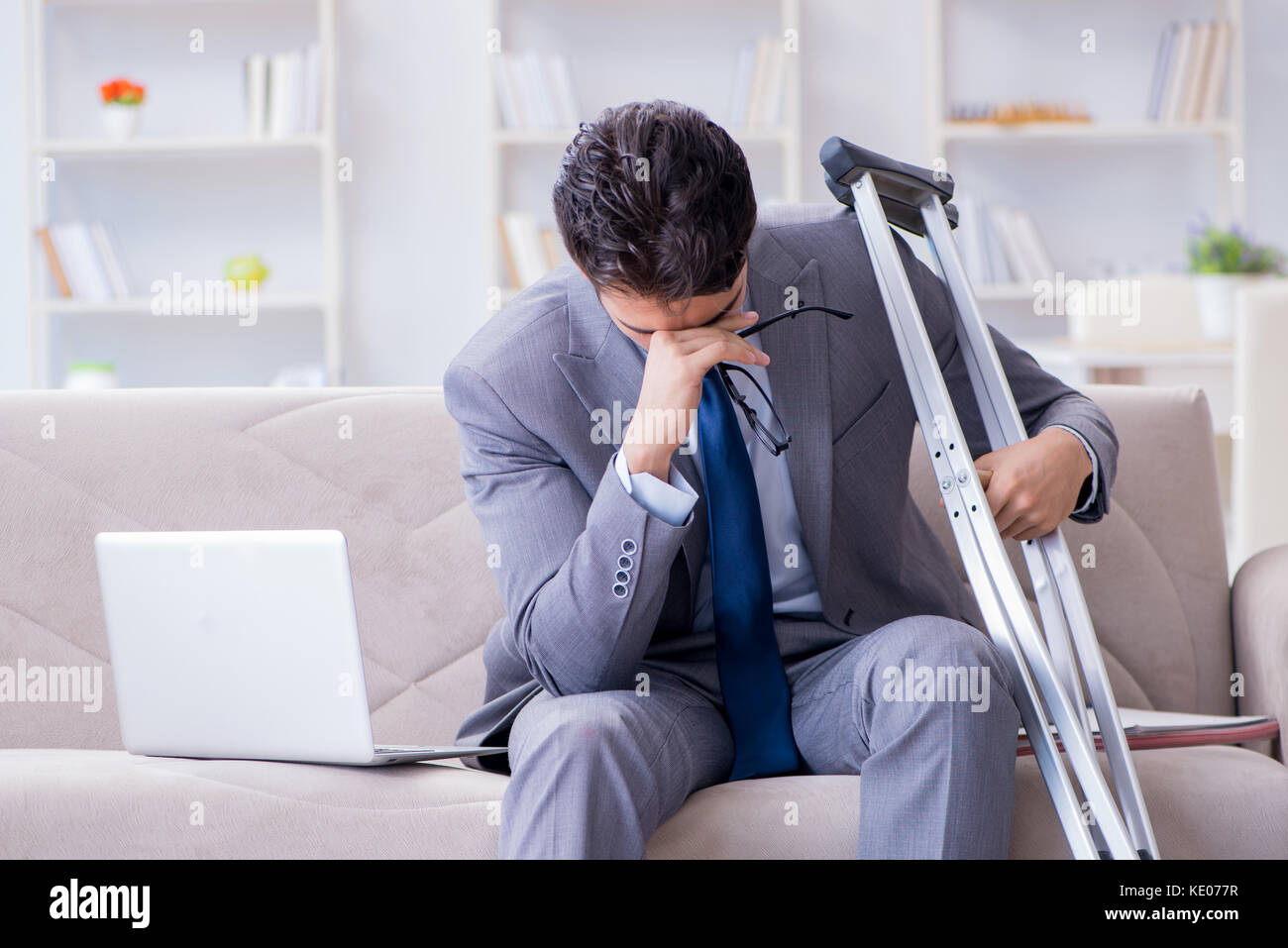 Businessman with crutches and broken leg at home working Stock Photo ...