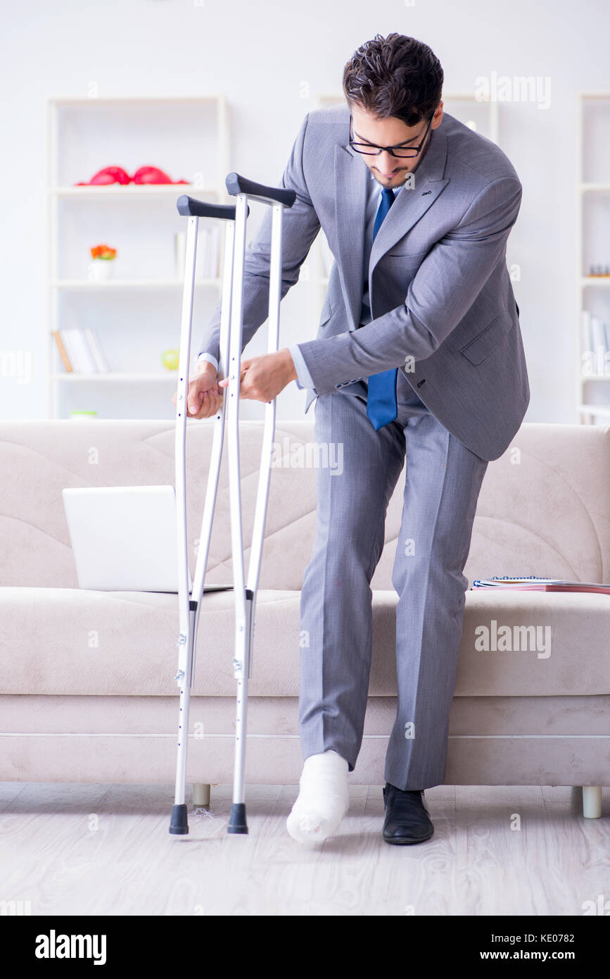Businessman with crutches and broken leg at home working Stock Photo ...