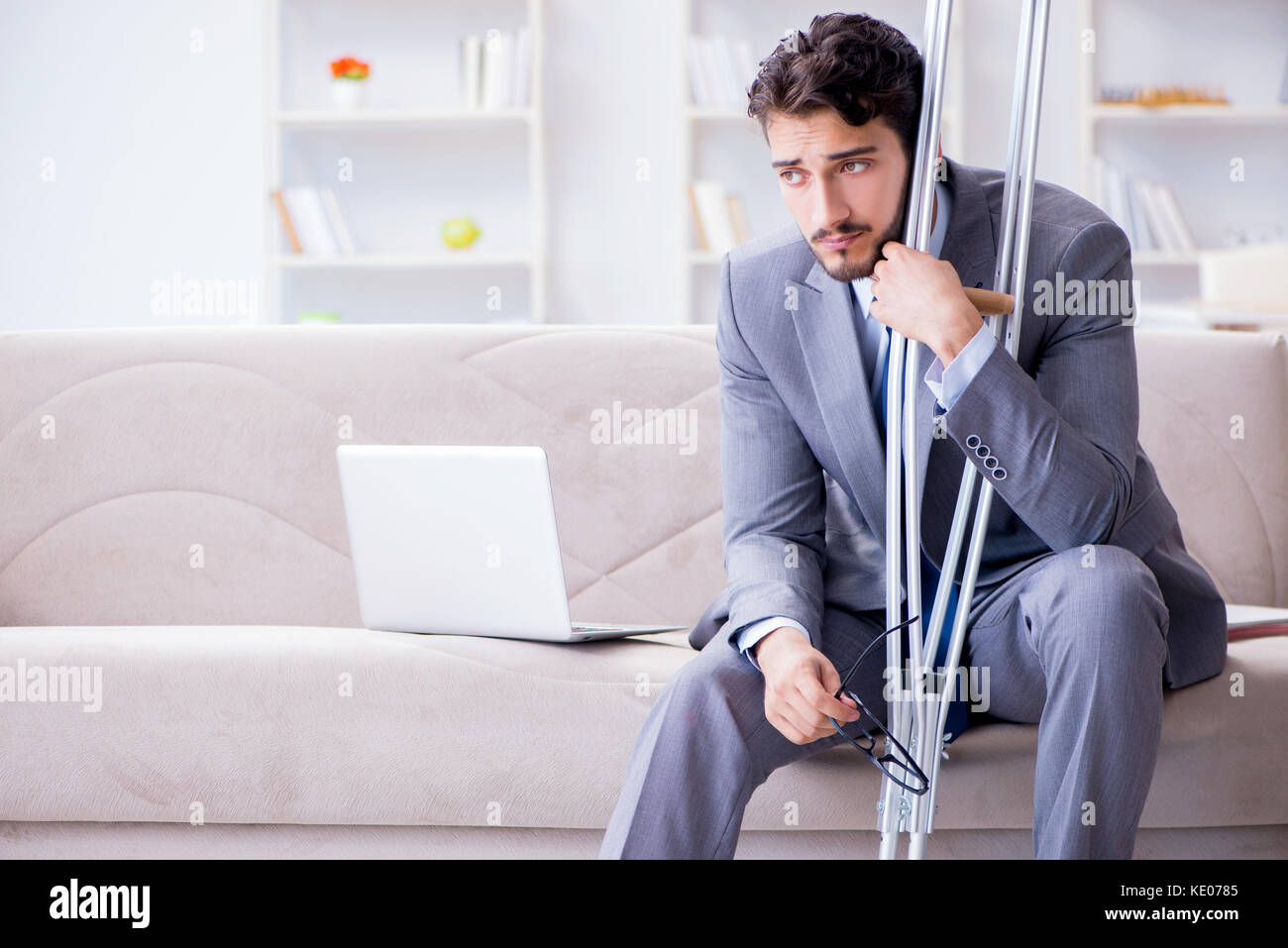 Businessman with crutches and broken leg at home working Stock Photo ...