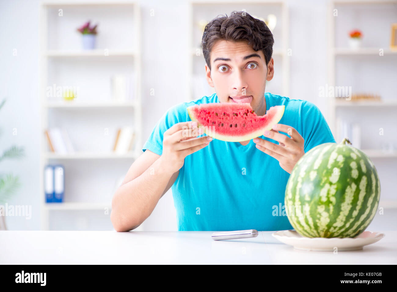 Man eating watermelon at home Stock Photo - Alamy