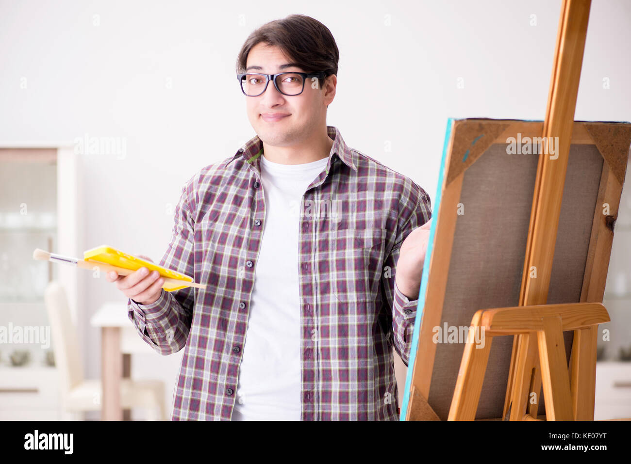Young male artist drawing pictures in bright studio Stock Photo - Alamy