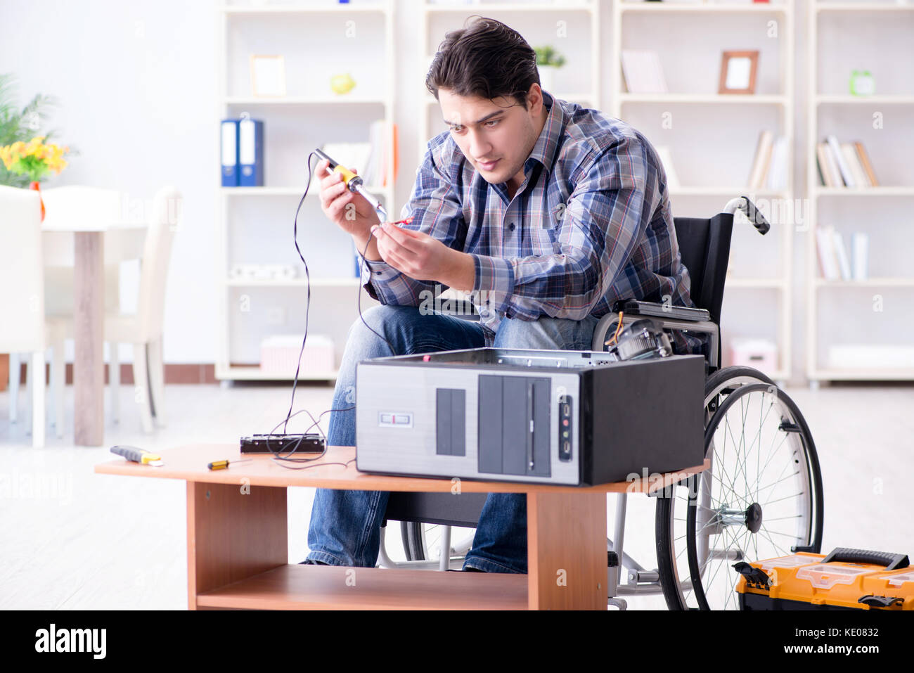 Disabled man on wheelchair repairing computer Stock Photo - Alamy