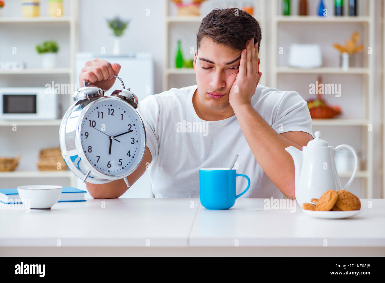 Man with alarm clock falling asleep at breakfast Stock Photo - Alamy