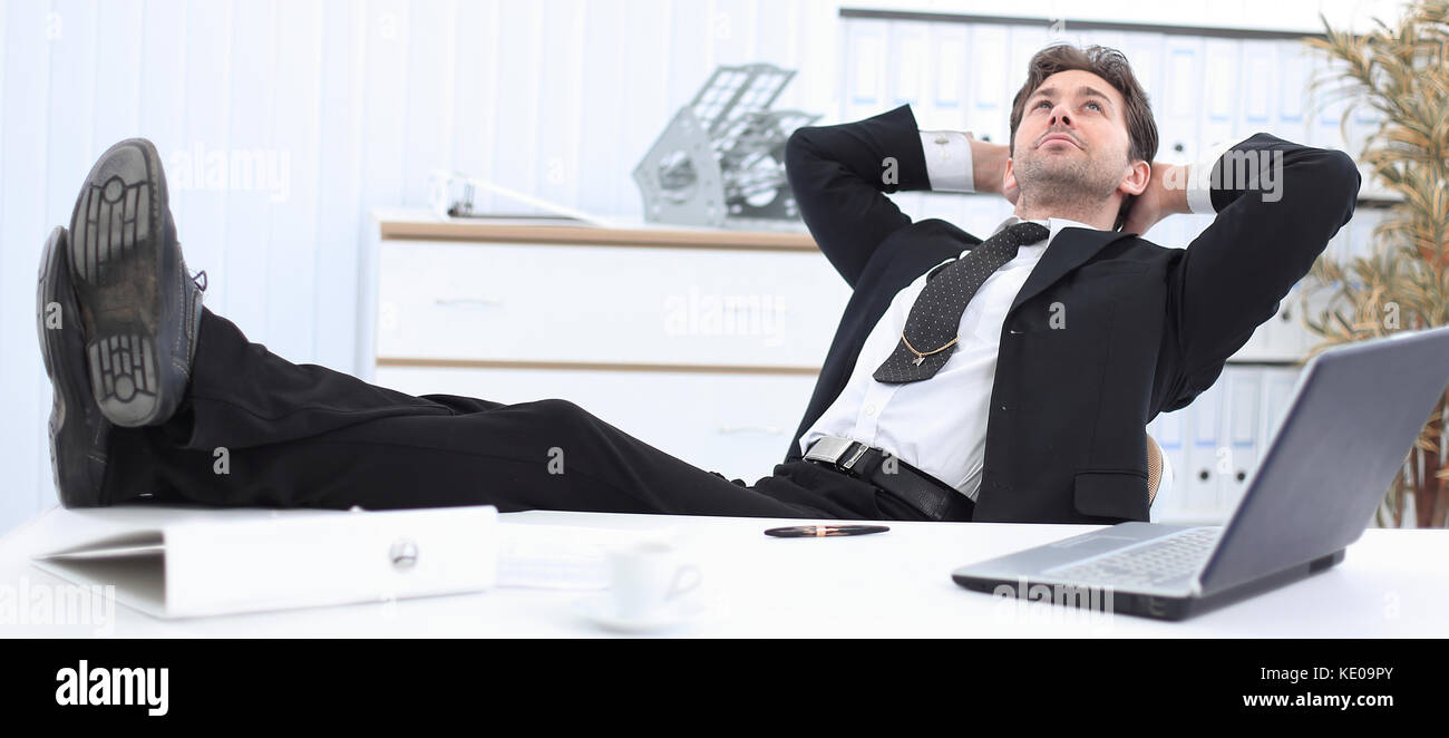businessman relaxes sitting behind a Desk Stock Photo - Alamy