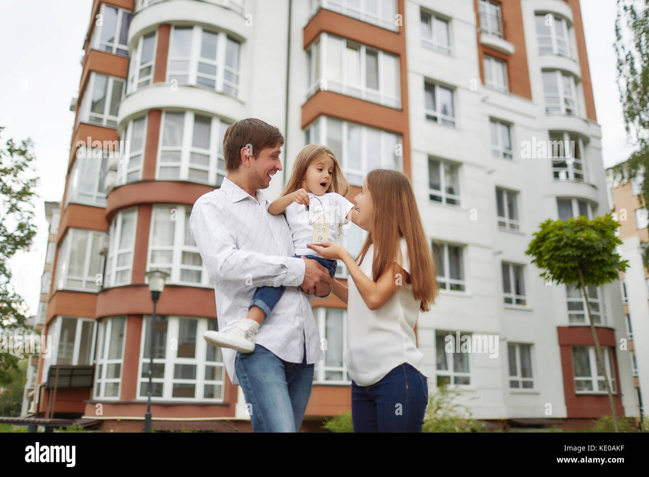 Happy family in front of new apartment building Stock Photo - Alamy