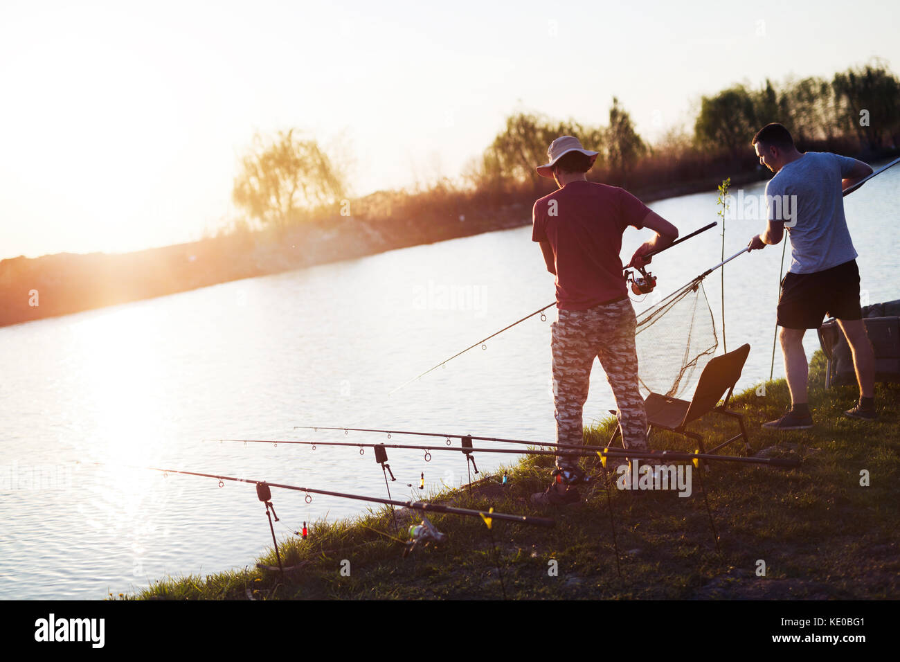Young man fishing on lake at sunset enjoying hobby Stock Photo - Alamy