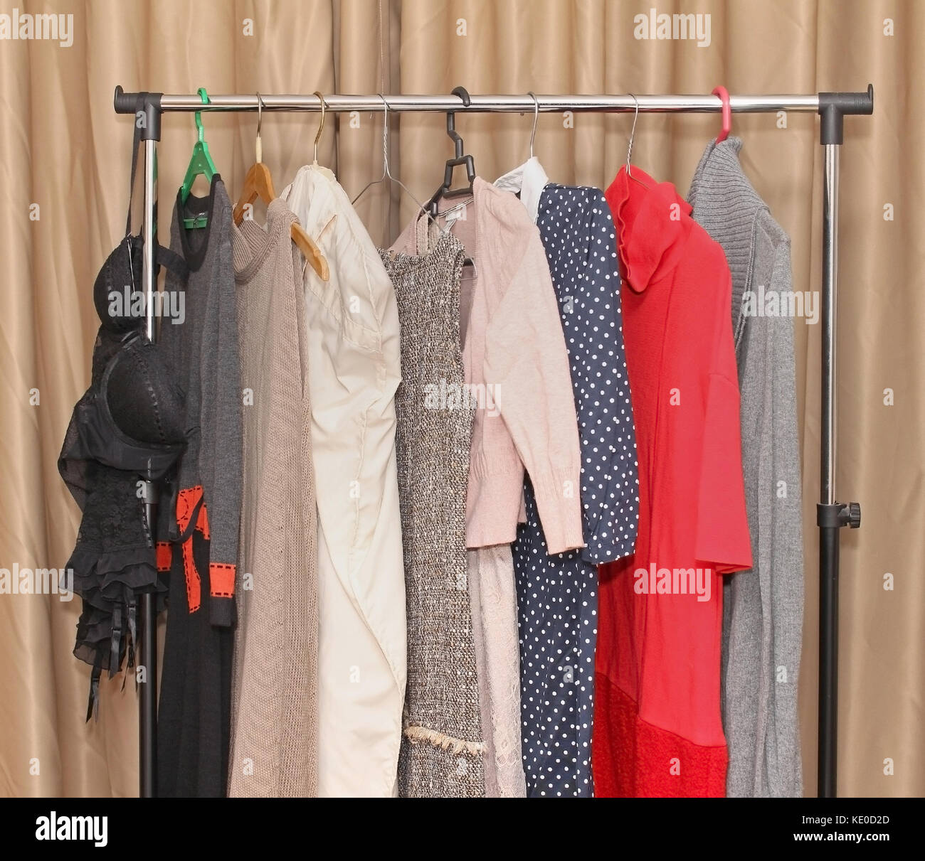 Fashionable modern female clothes hanging from rack Stock Photo - Alamy