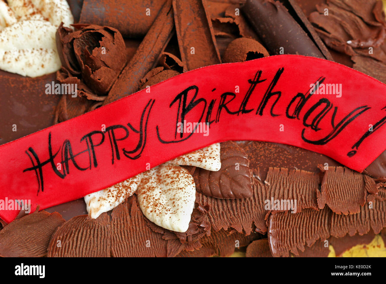 Red ribbon happy birthday sign on chocolate cake Stock Photo - Alamy