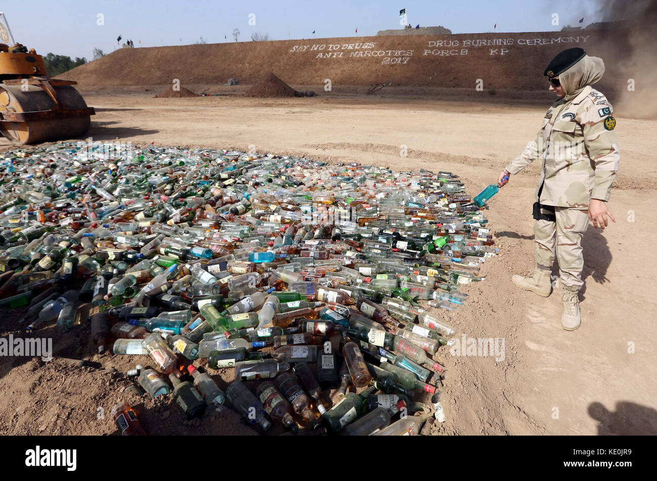 Anti-Narcotics Force (ANF) officials stand alert near burning pile of ...