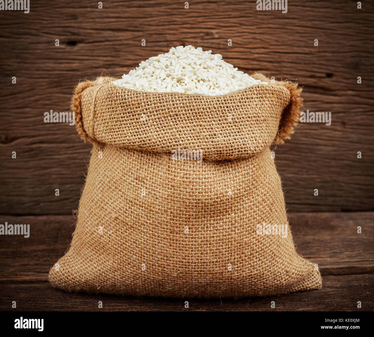 rice in burlap sack on wooden background Stock Photo - Alamy