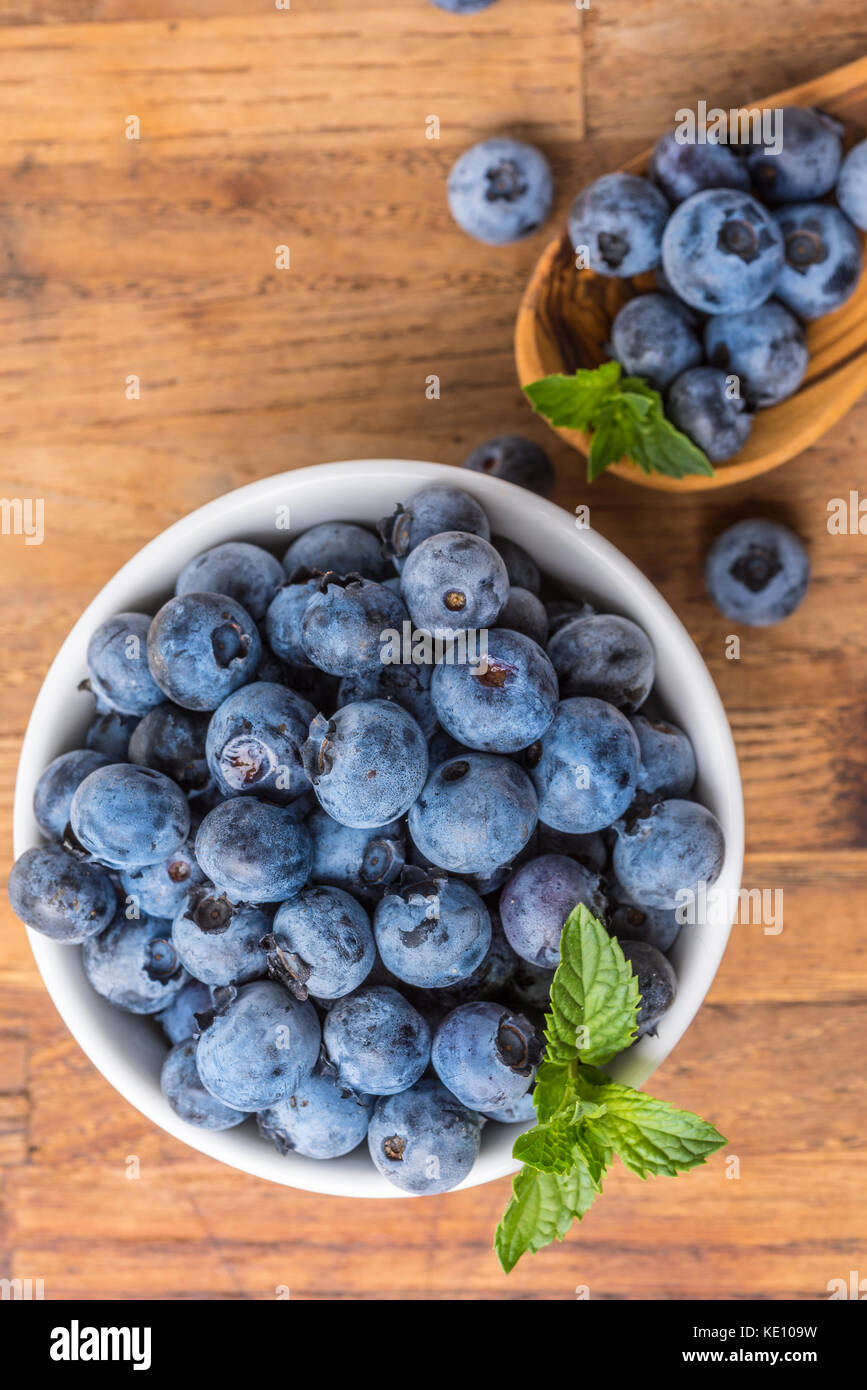 Blueberries on a rustic table with spoon and green leaves Stock Photo ...