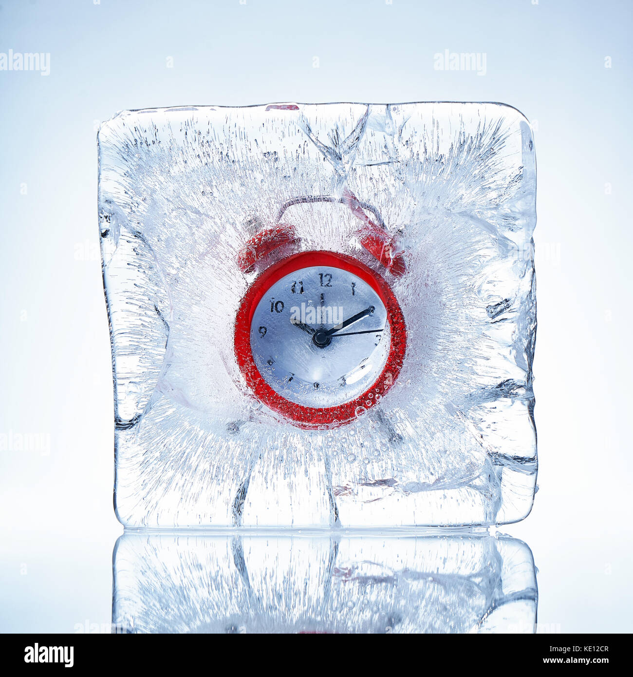 Red alarm clock in a piece of ice Stock Photo - Alamy