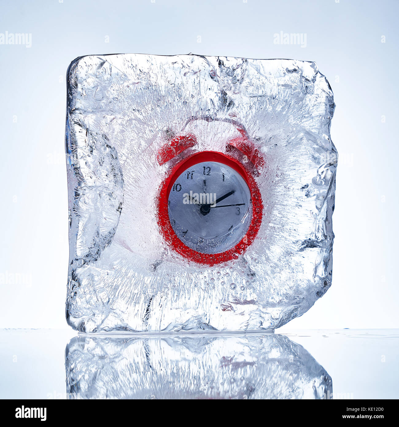 Red alarm clock in a piece of ice Stock Photo - Alamy
