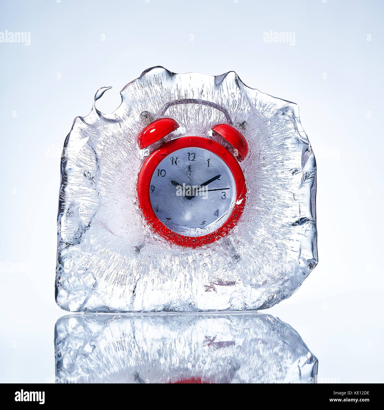 Red alarm clock in a piece of ice Stock Photo - Alamy