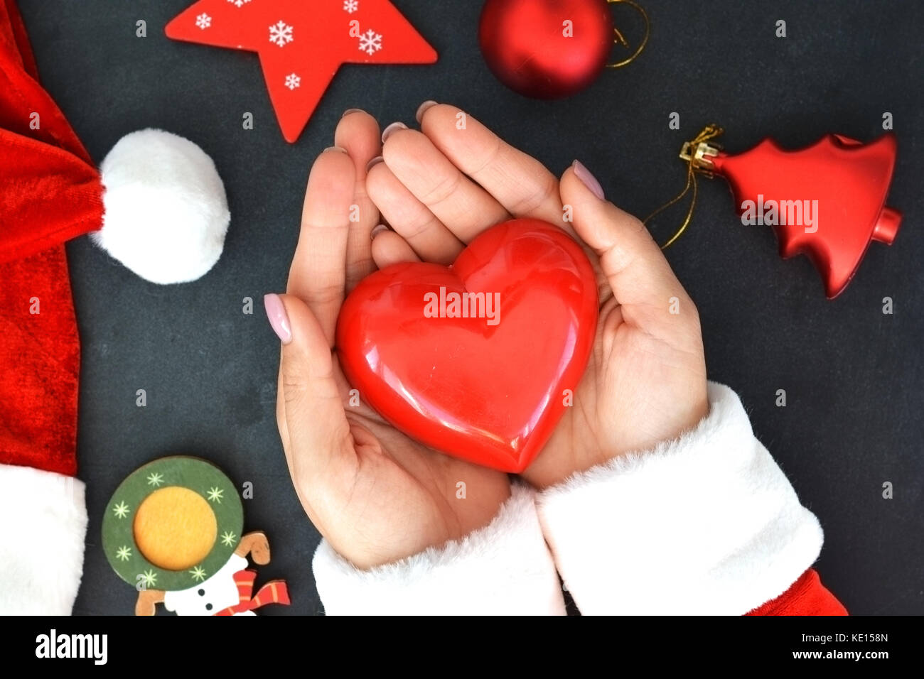 Close up of Santa’s hands holding red heart shape on Christmas ...