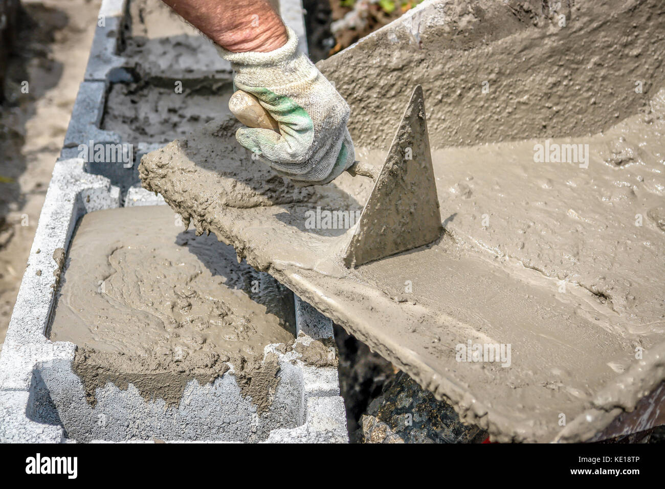 Closeup of mason hand pouring out mortar into concrete shuttering ...
