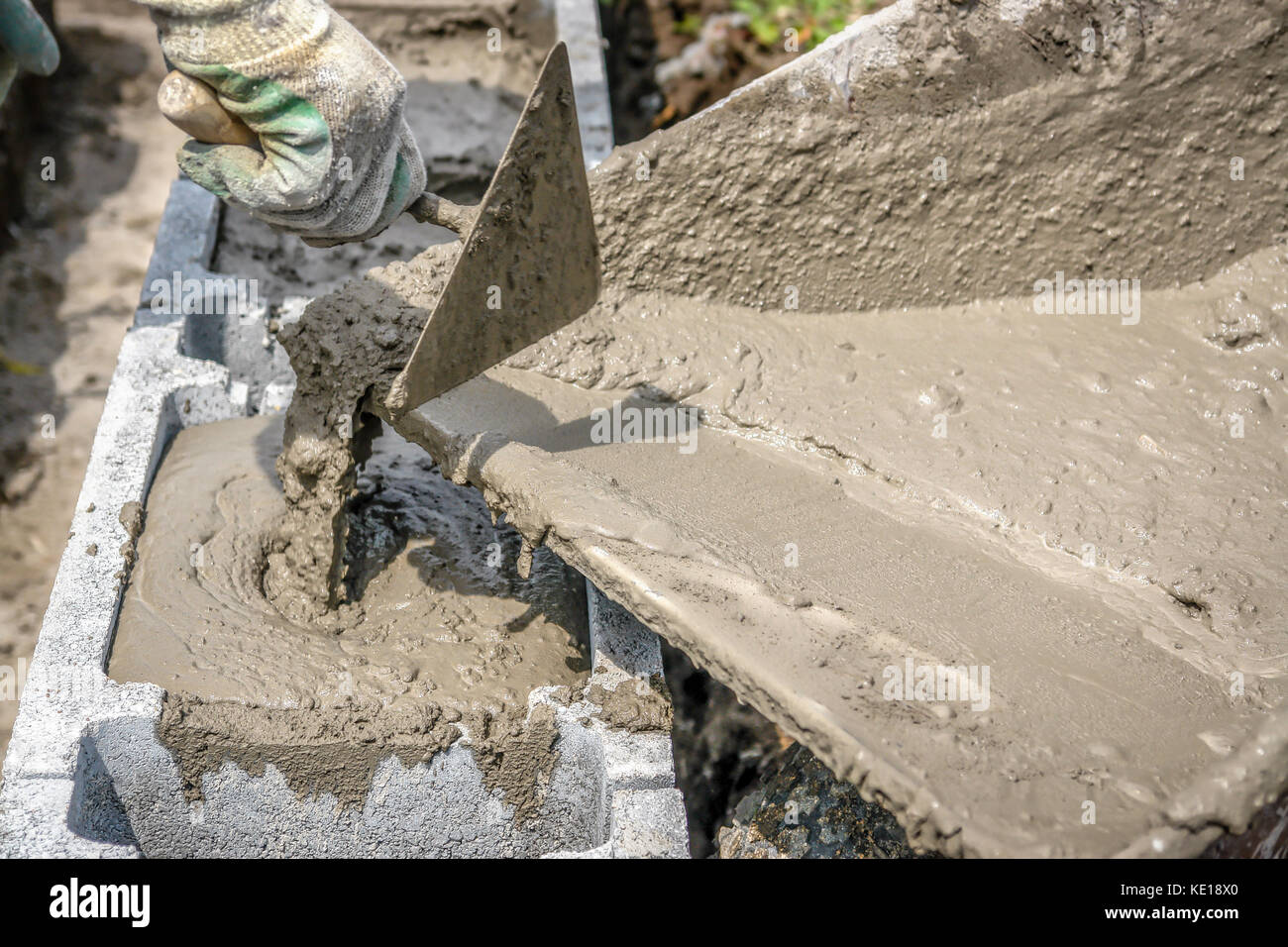 Closeup of mason hand pouring out mortar into concrete shuttering ...