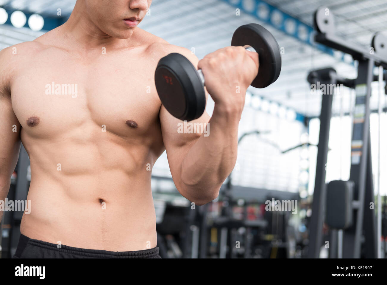 young man lift dumbbell in gym. bodybuilder male working out in fitness ...
