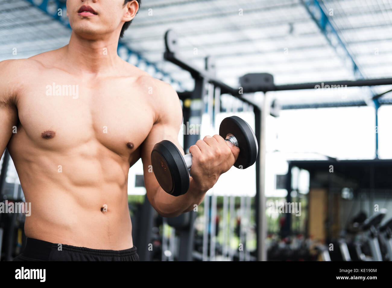 young man lift dumbbell in gym. bodybuilder male working out in fitness ...