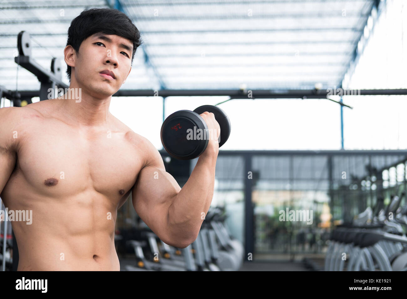 young man lift dumbbell in gym. bodybuilder male working out in fitness ...