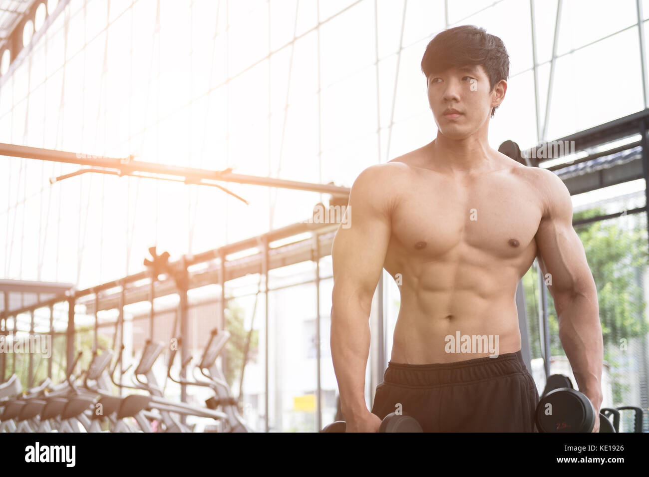 young man lift dumbbell in gym. bodybuilder male working out in fitness ...