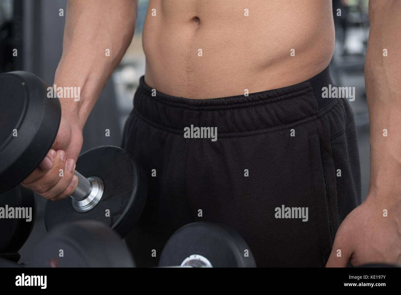 young man execute exercise in fitness center. male athlete choose ...