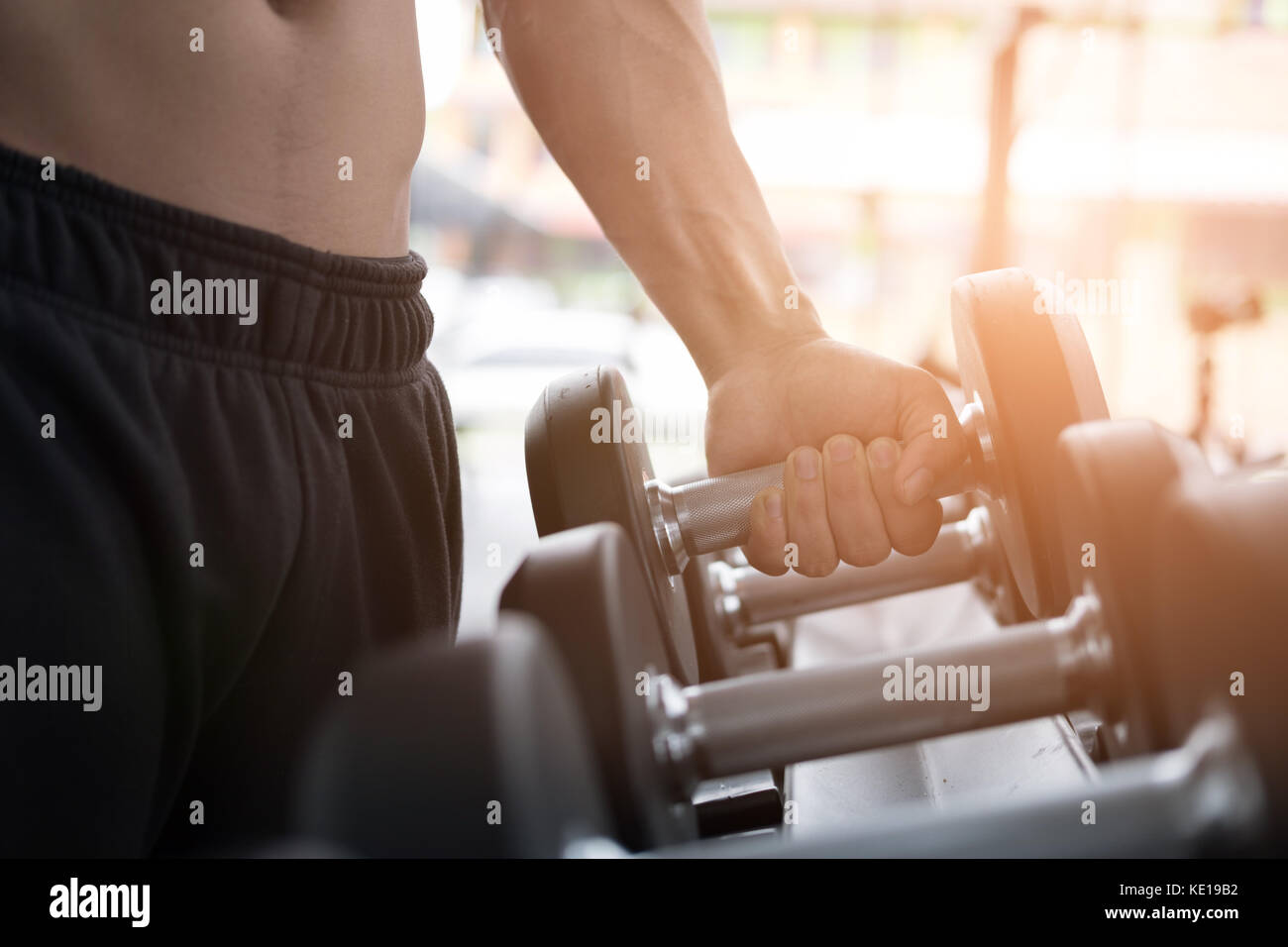 young man execute exercise in fitness center. male athlete choose ...