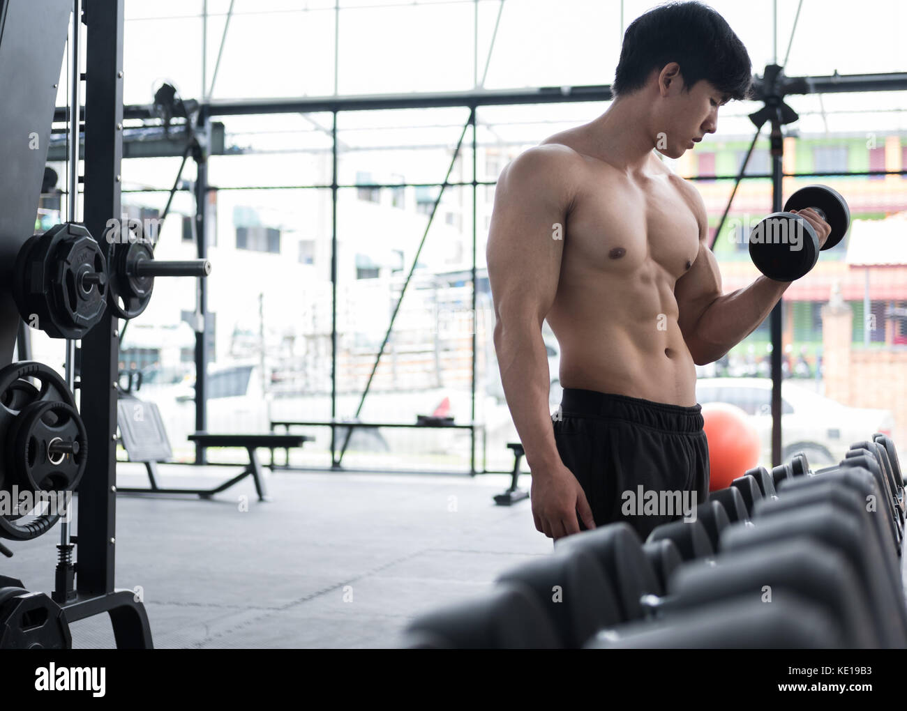 young man lift dumbbell in gym. bodybuilder male working out in fitness ...
