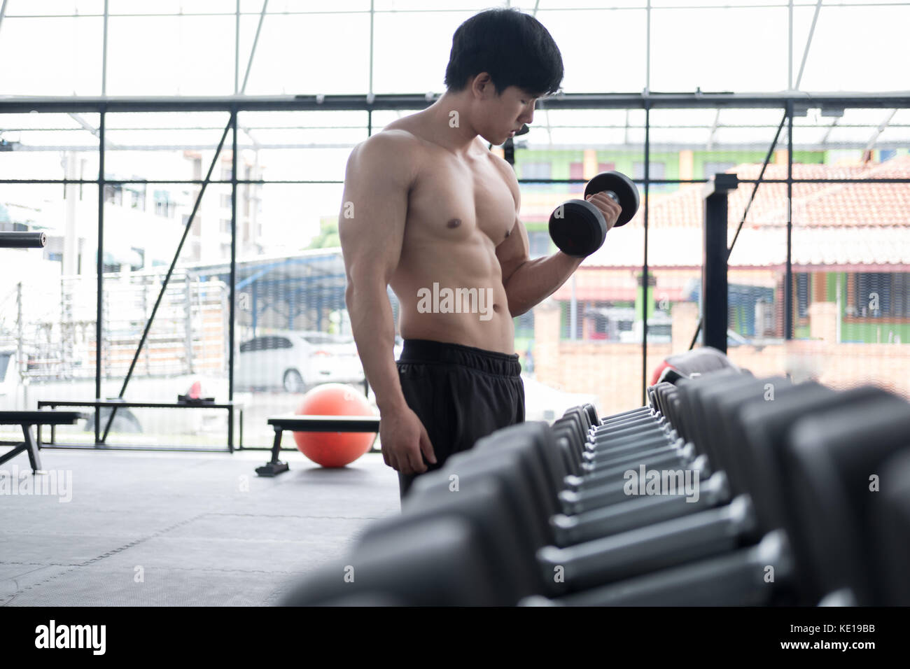 young man lift dumbbell in gym. bodybuilder male working out in fitness ...