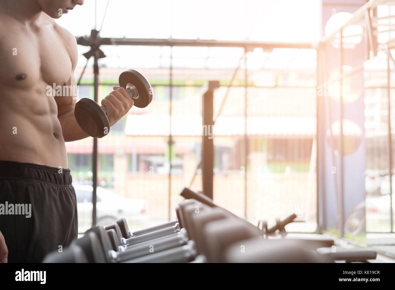 young man lift dumbbell in gym. bodybuilder male working out in fitness ...