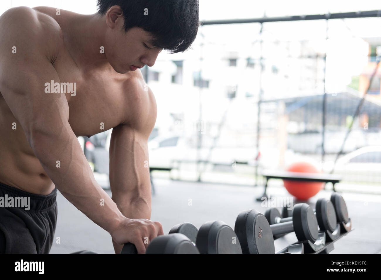 young man execute exercise in fitness center. male athlete choose ...