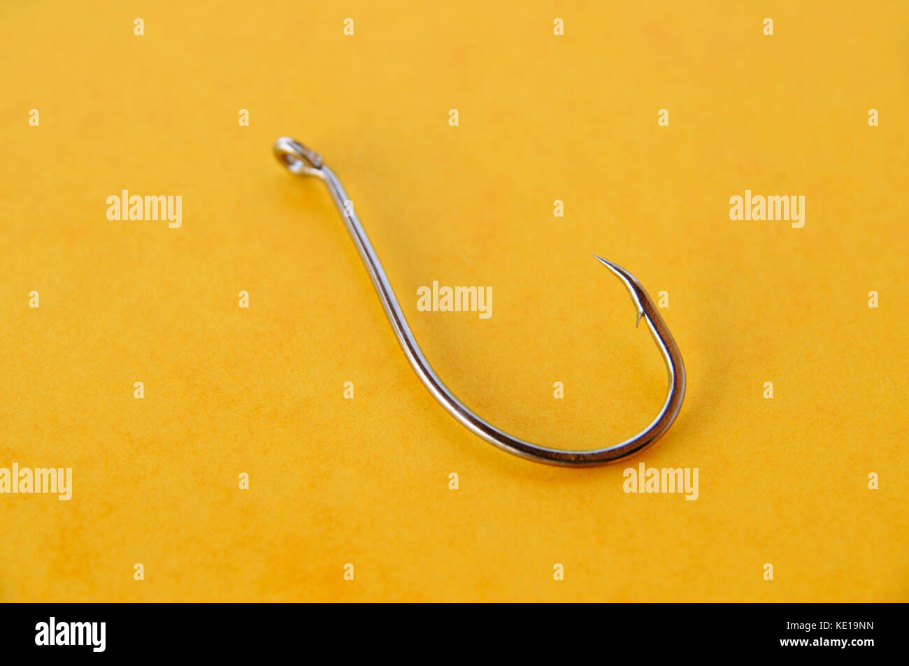 Fishing hook on yellow background with copy space Stock Photo - Alamy
