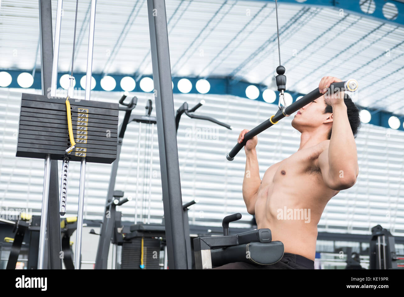 young man execute exercise with weightlifting machine in fitness center ...