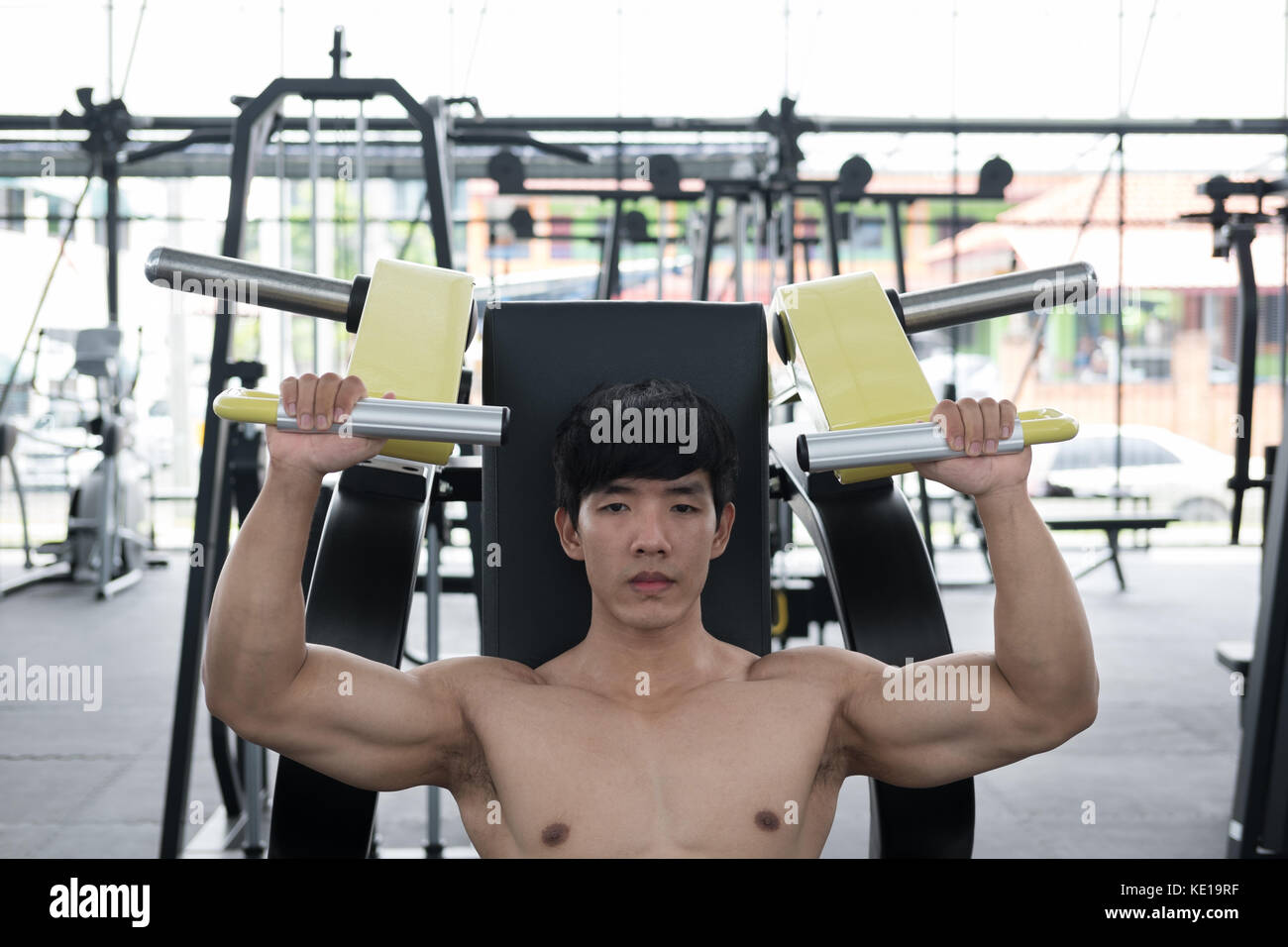 young man execute exercise with weightlifting machine in fitness center ...