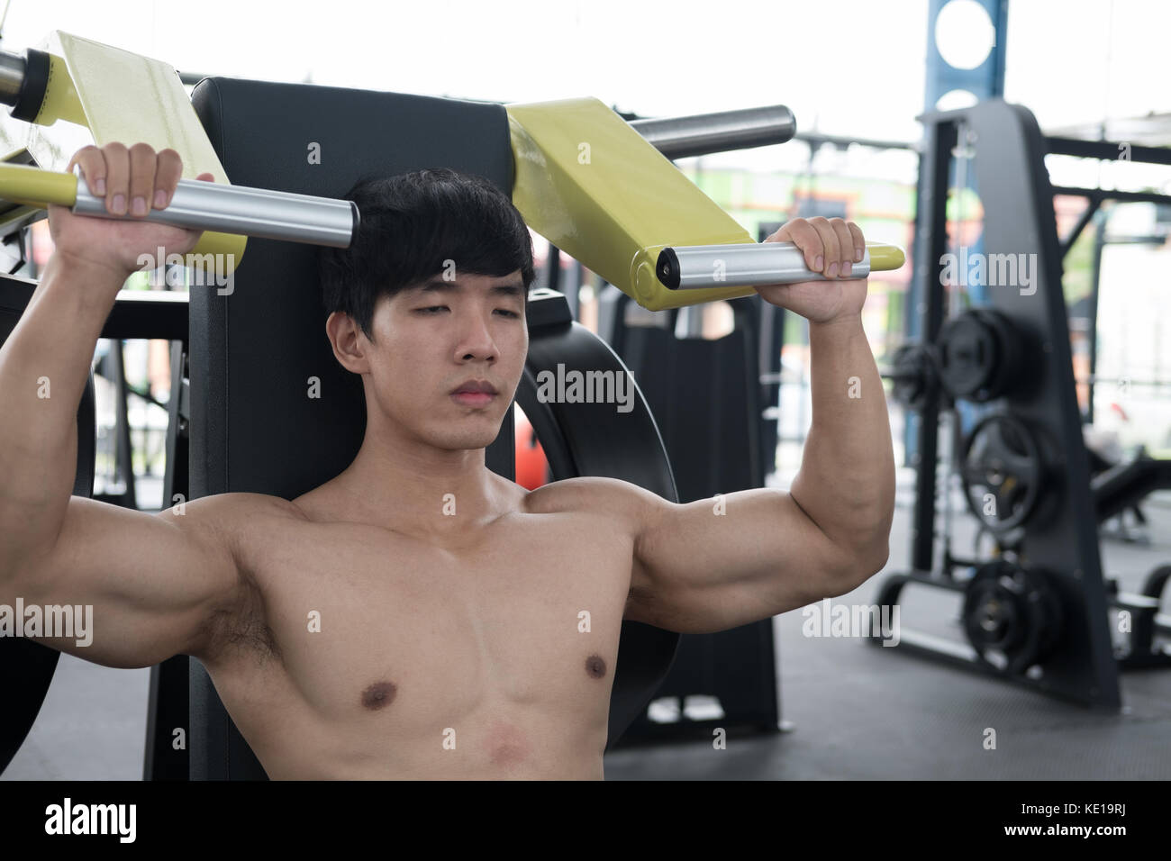 young man execute exercise with weightlifting machine in fitness center ...