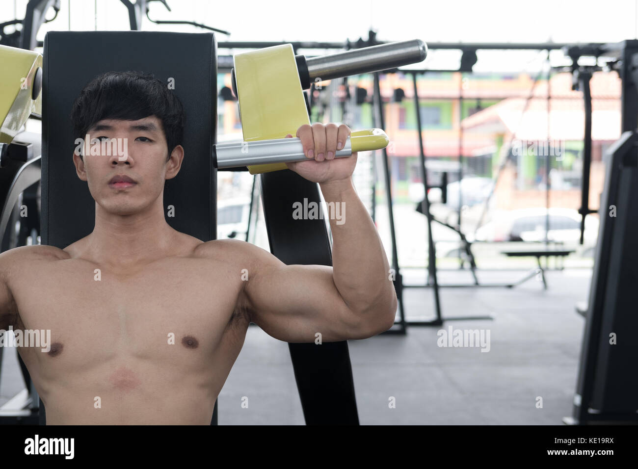 young man execute exercise with weightlifting machine in fitness center ...
