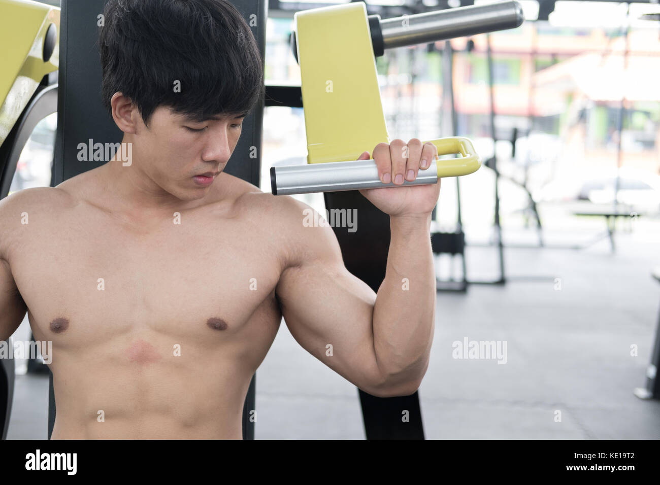 young man execute exercise with weightlifting machine in fitness center ...
