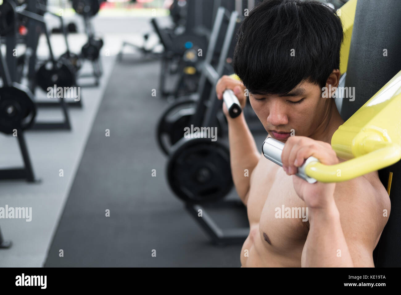 young man execute exercise with weightlifting machine in fitness center ...