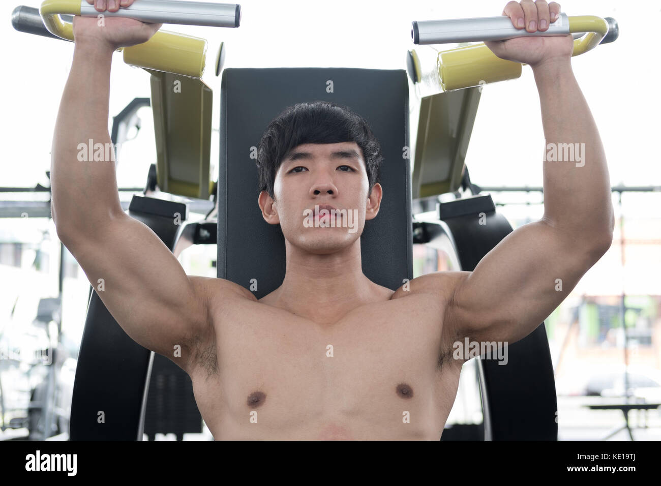 young man execute exercise with weightlifting machine in fitness center ...