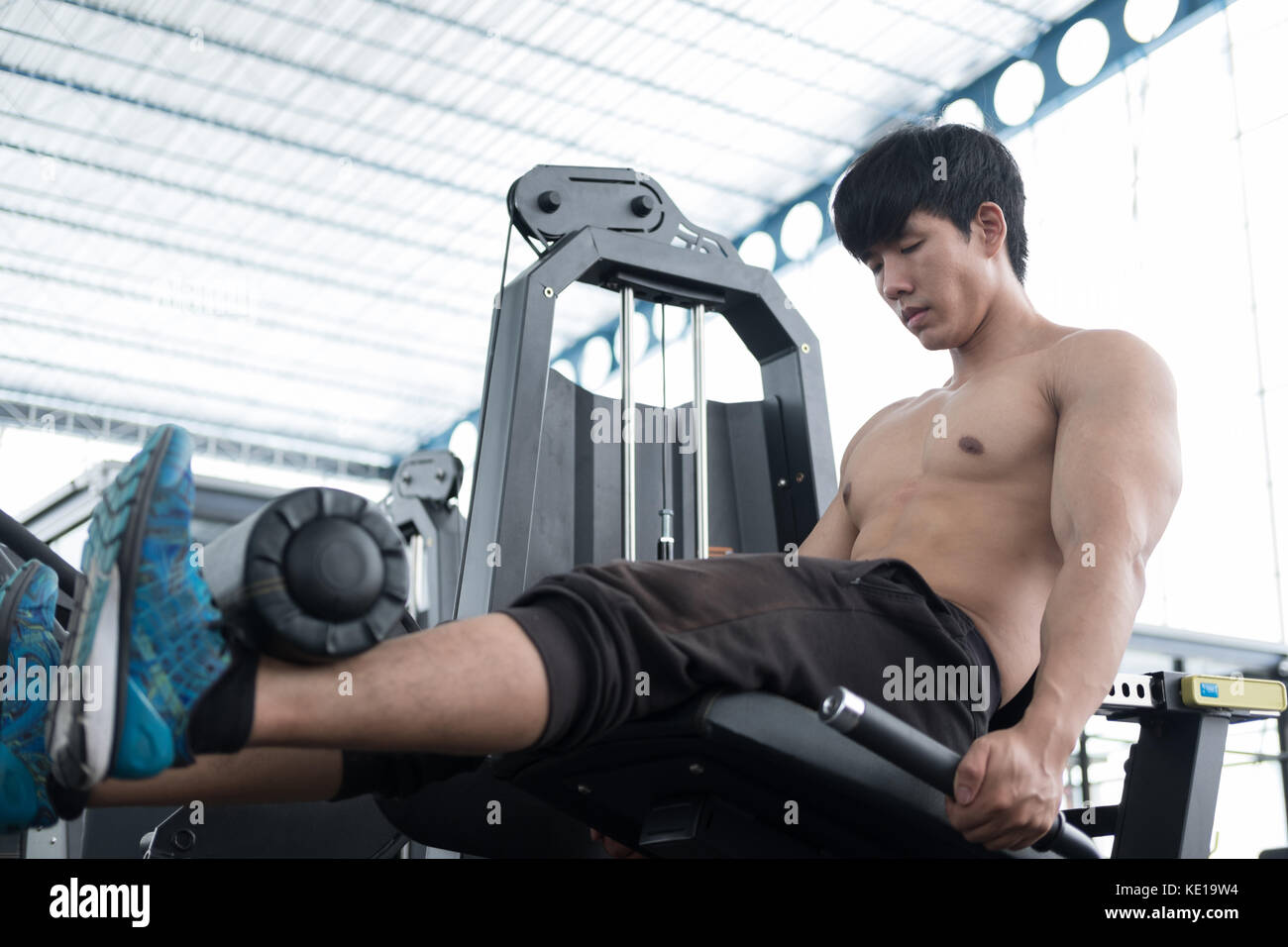 young man execute exercise with weightlifting machine in fitness center ...