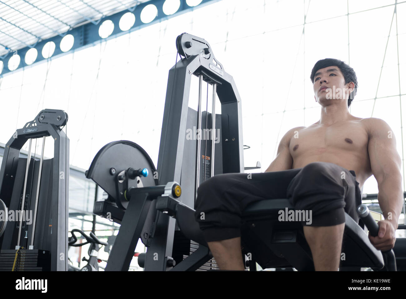 young man execute exercise with weightlifting machine in fitness center ...