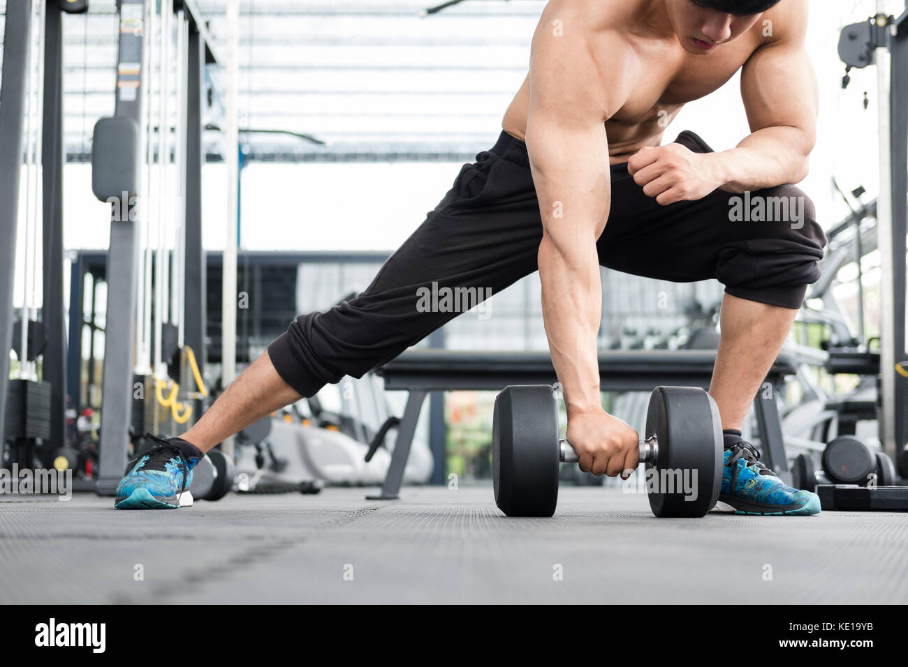 young man lift dumbbell in gym. bodybuilder male working out in fitness ...